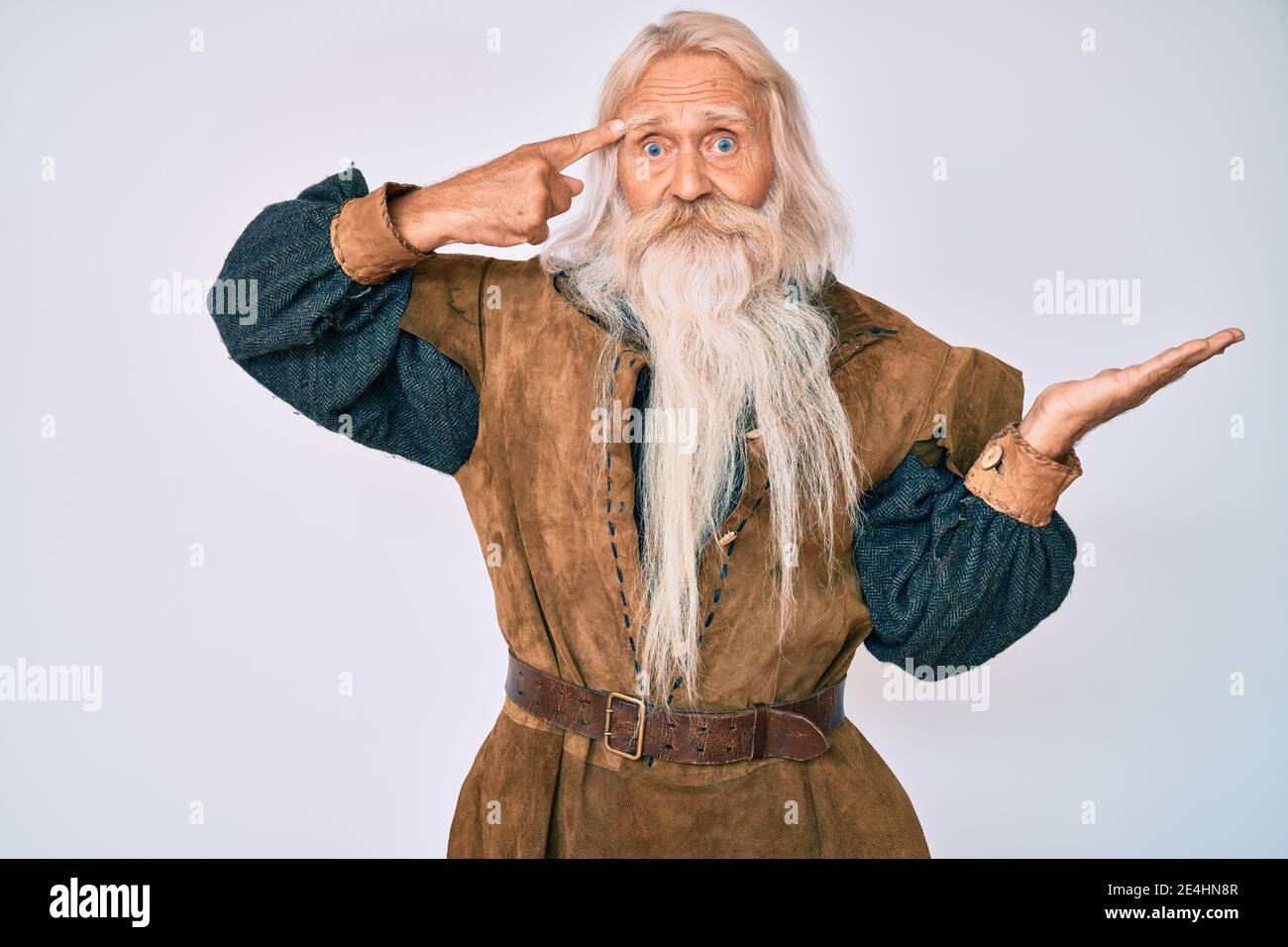 Old senior man with grey hair and long beard wearing viking traditional ...