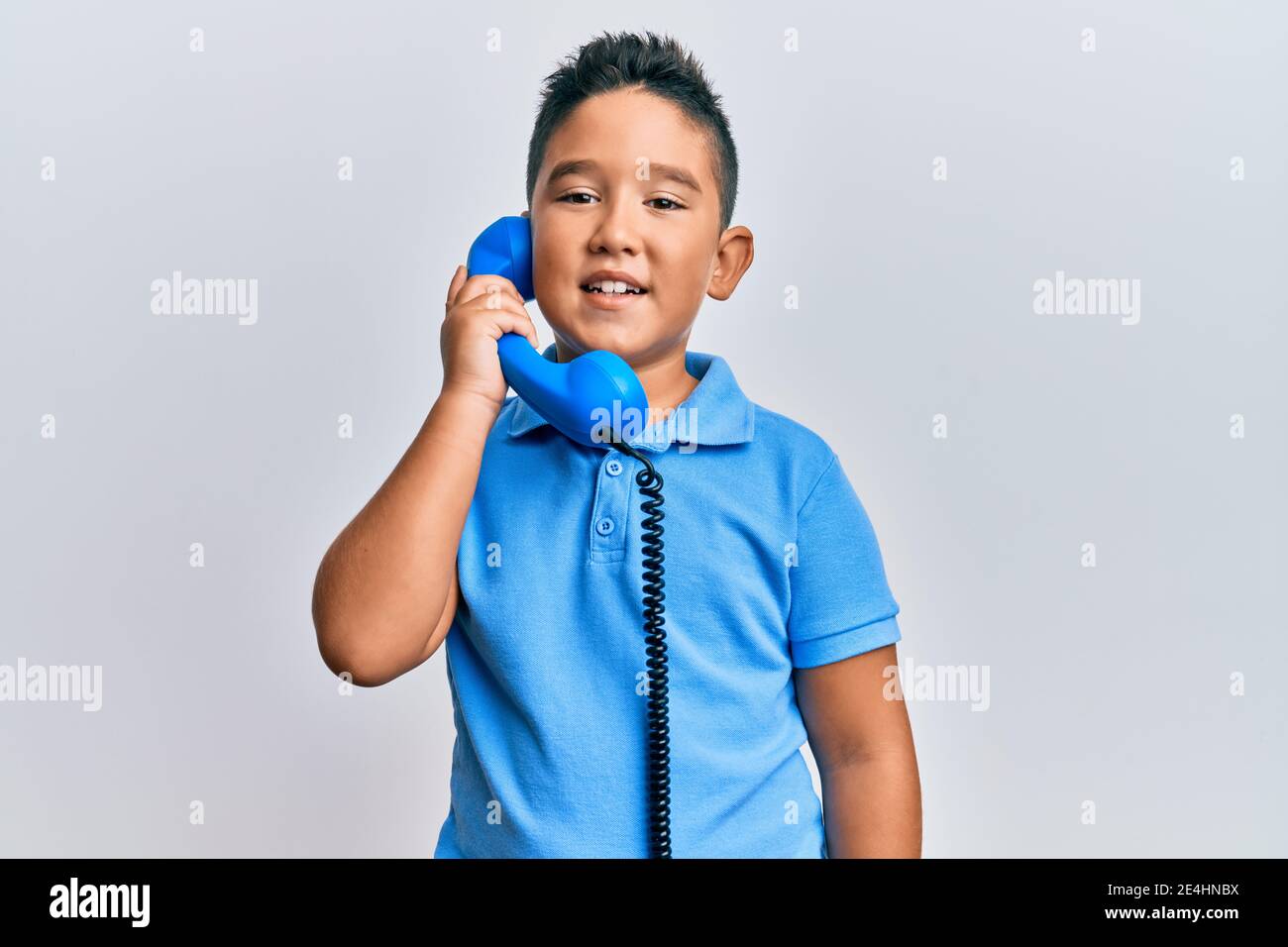Little boy hispanic kid talking through vintage telephone looking ...