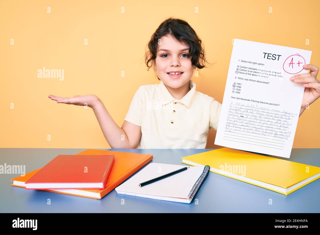 Cute hispanic child showing a passed exam sitting on the desk ...