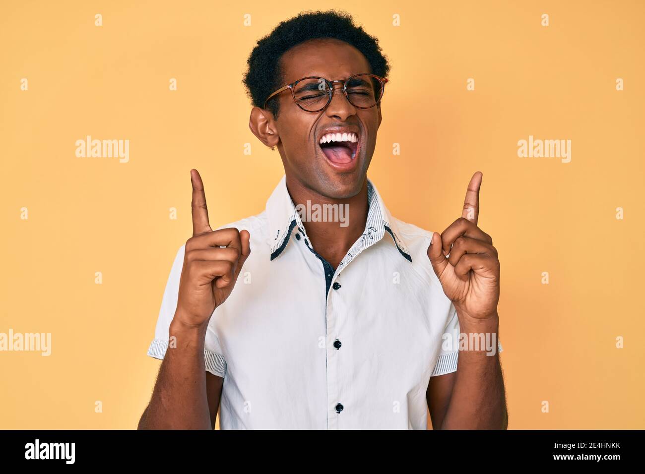African handsome man pointing up with fingers angry and mad screaming ...
