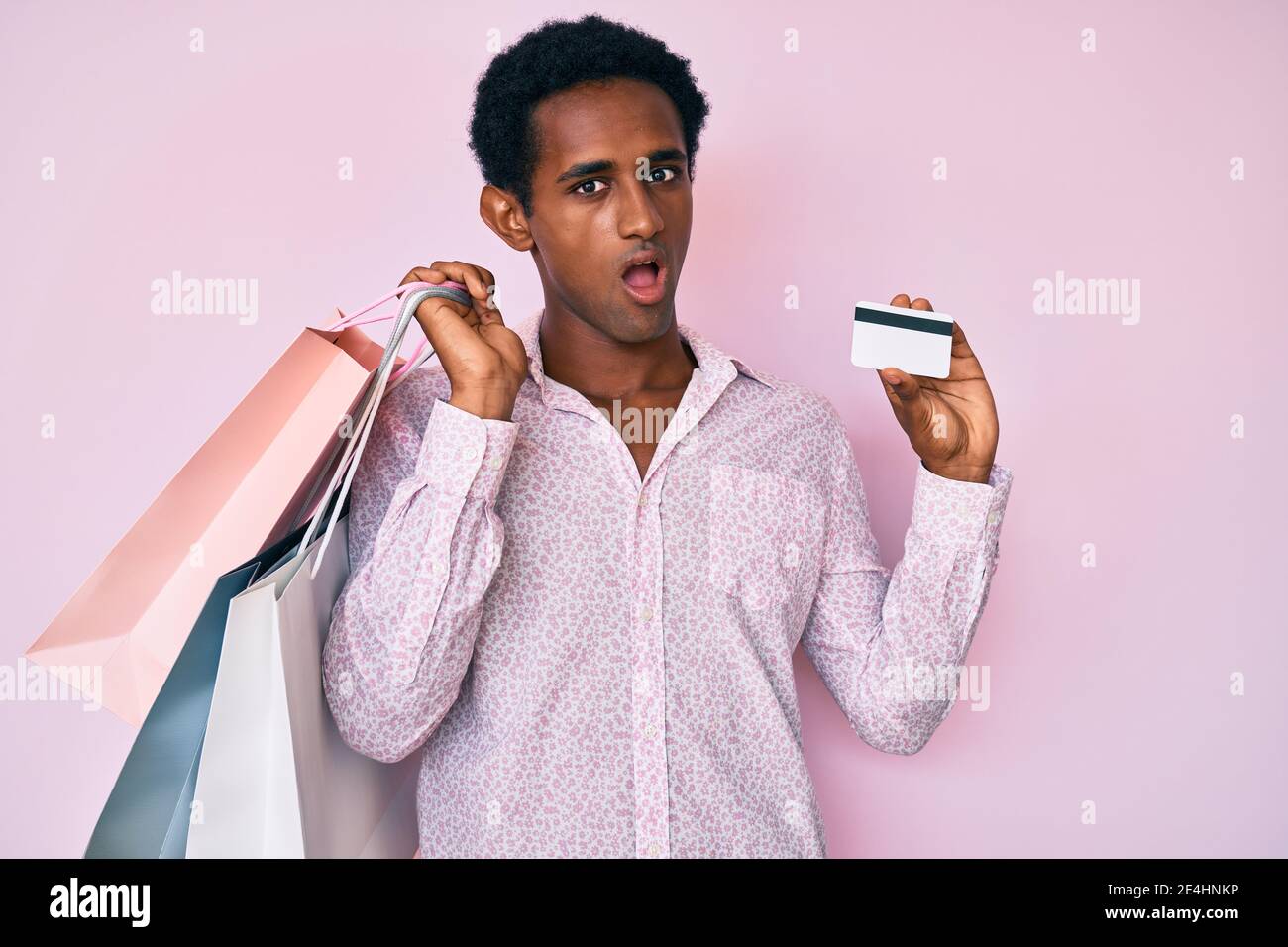 African handsome man holding shopping bags and credit card in shock ...