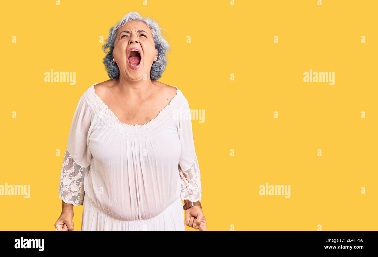 Senior woman with gray hair wearing bohemian style angry and mad ...