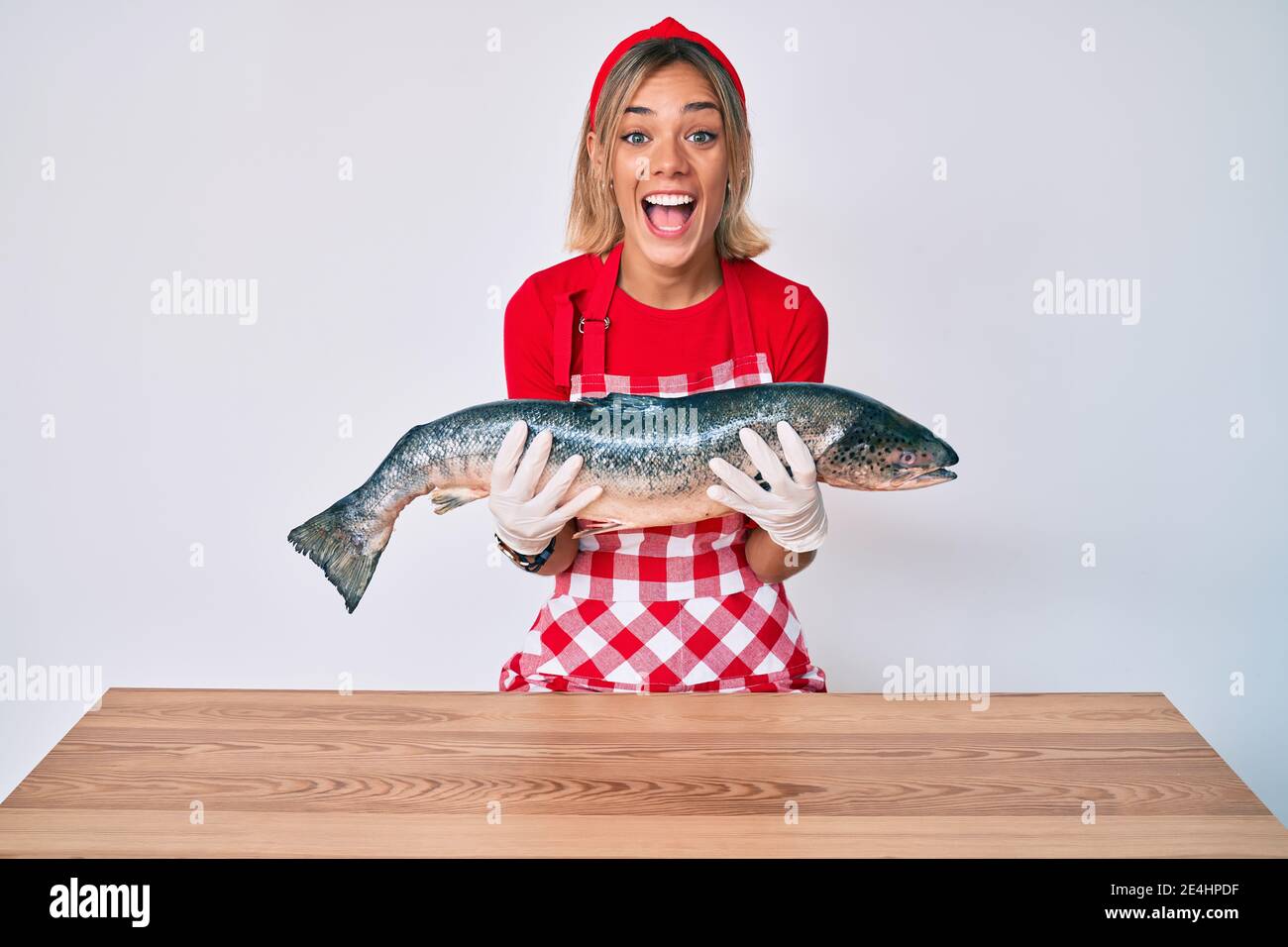 Beautiful caucasian woman fishmonger selling fresh raw salmon smiling ...