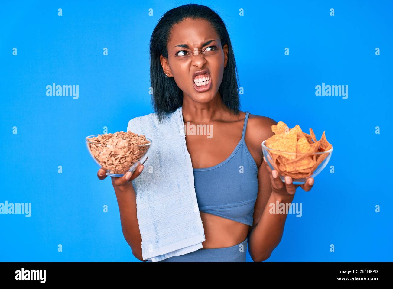 Young african american woman wearing sportswear holding nachos and ...