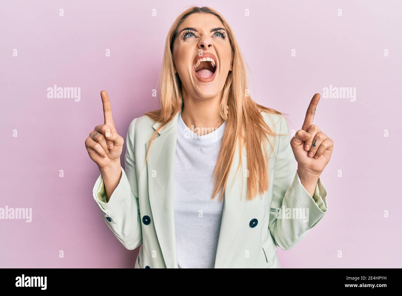 Young caucasian woman wearing business clothes pointing up with fingers ...