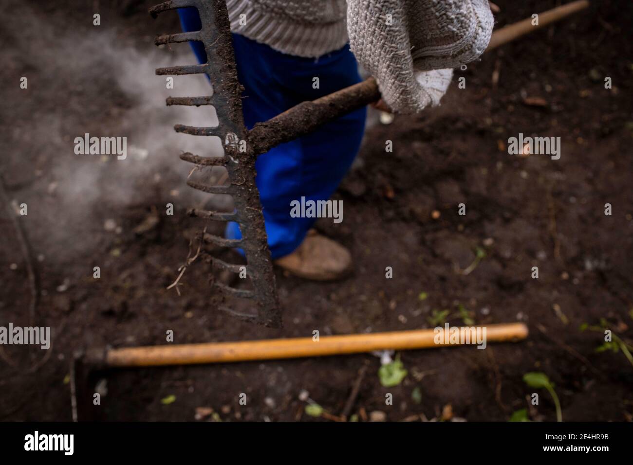 Worker carrying a rake and a hoe, smoke of a charcoal kiln Stock Photo ...