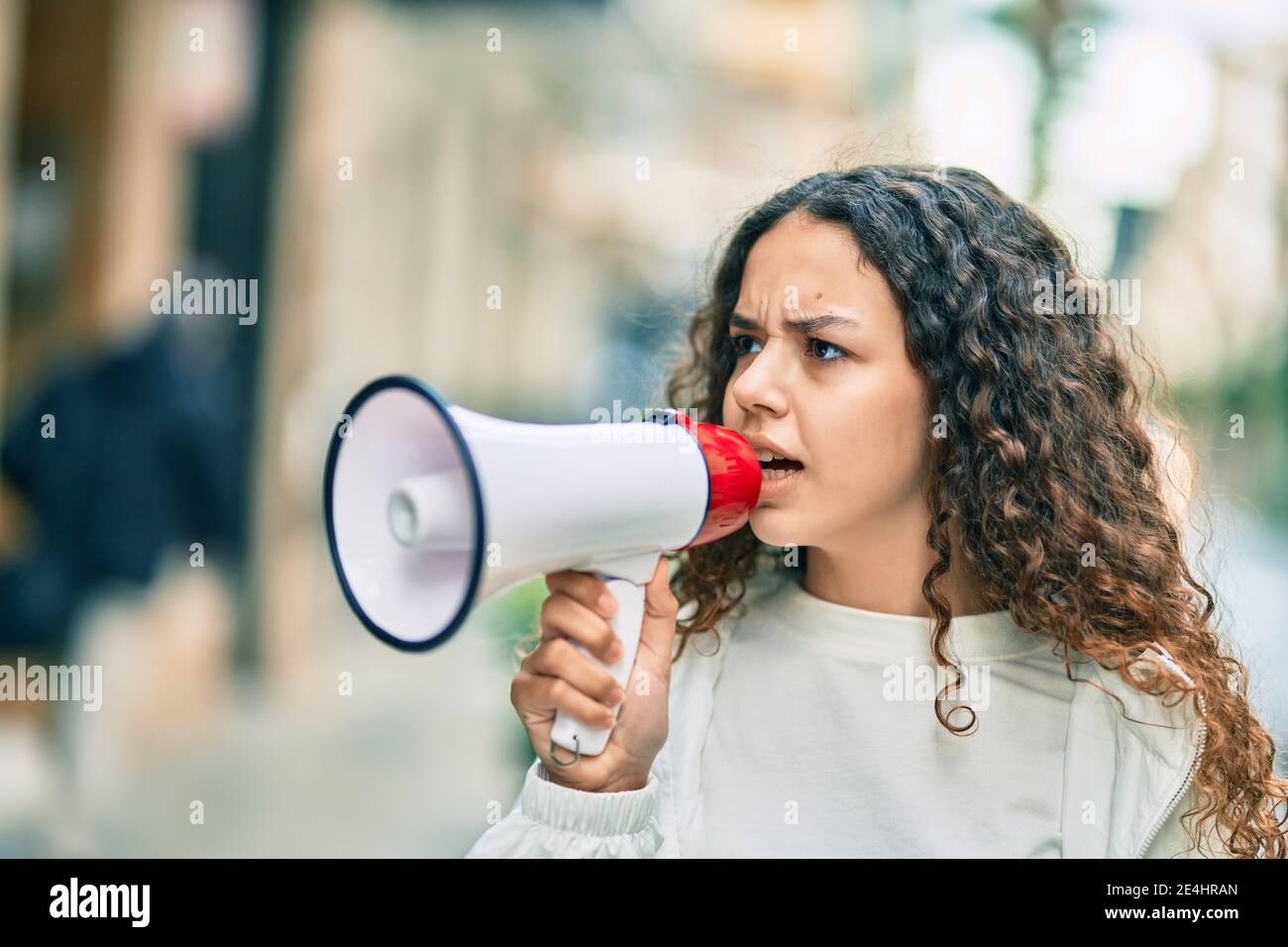 Hispanic child girl shouting angry using megaphone at the city Stock ...