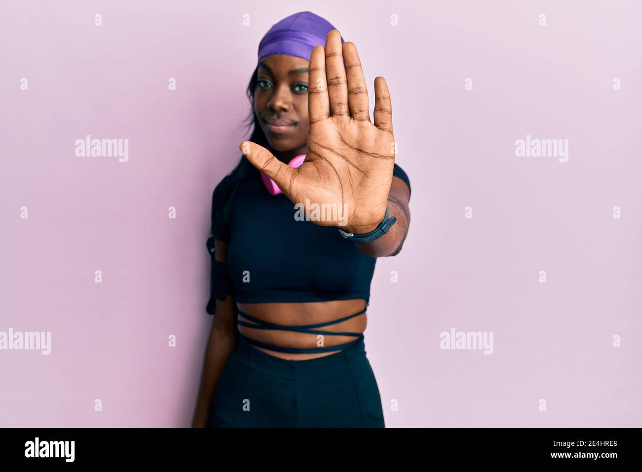 Young african american woman wearing gym clothes and using headphones ...