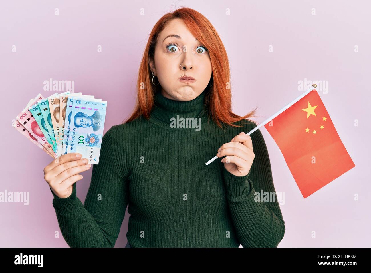 Beautiful redhead woman holding yuan chinese banknotes and china flag ...