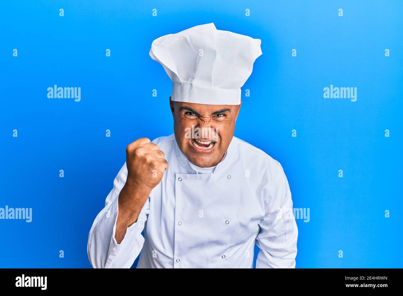 Mature middle east man wearing professional cook uniform and hat angry ...