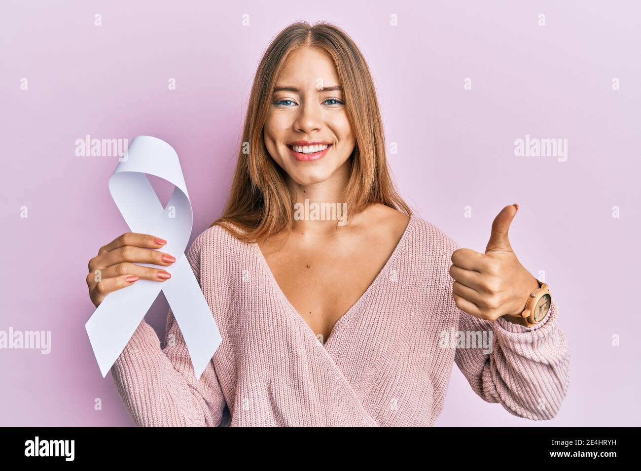 Beautiful young blonde woman holding white ribbon smiling happy and ...