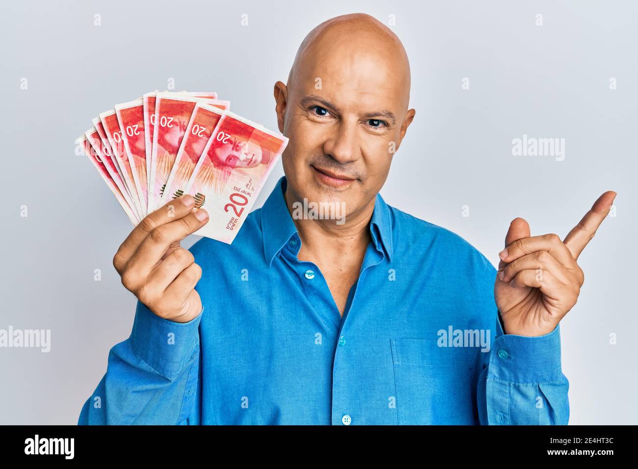 Middle age bald man holding 20 israel shekels banknotes smiling happy ...