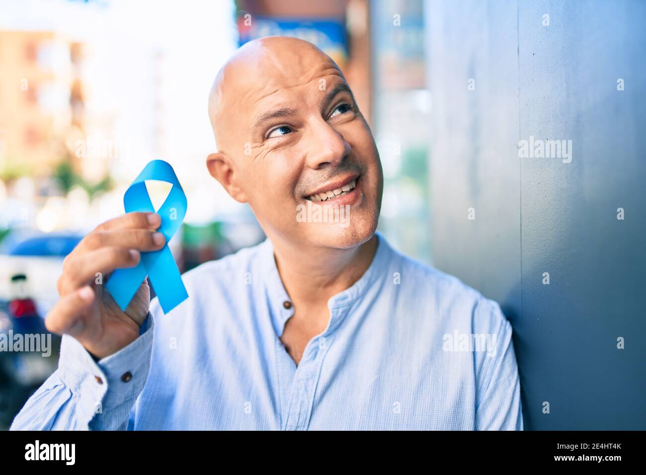 Middle age bald man smiling happy holding blue prostate cancer ribbon ...