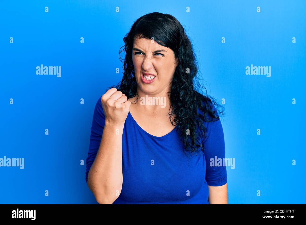 Plus size brunette woman wearing casual blue shirt angry and mad ...