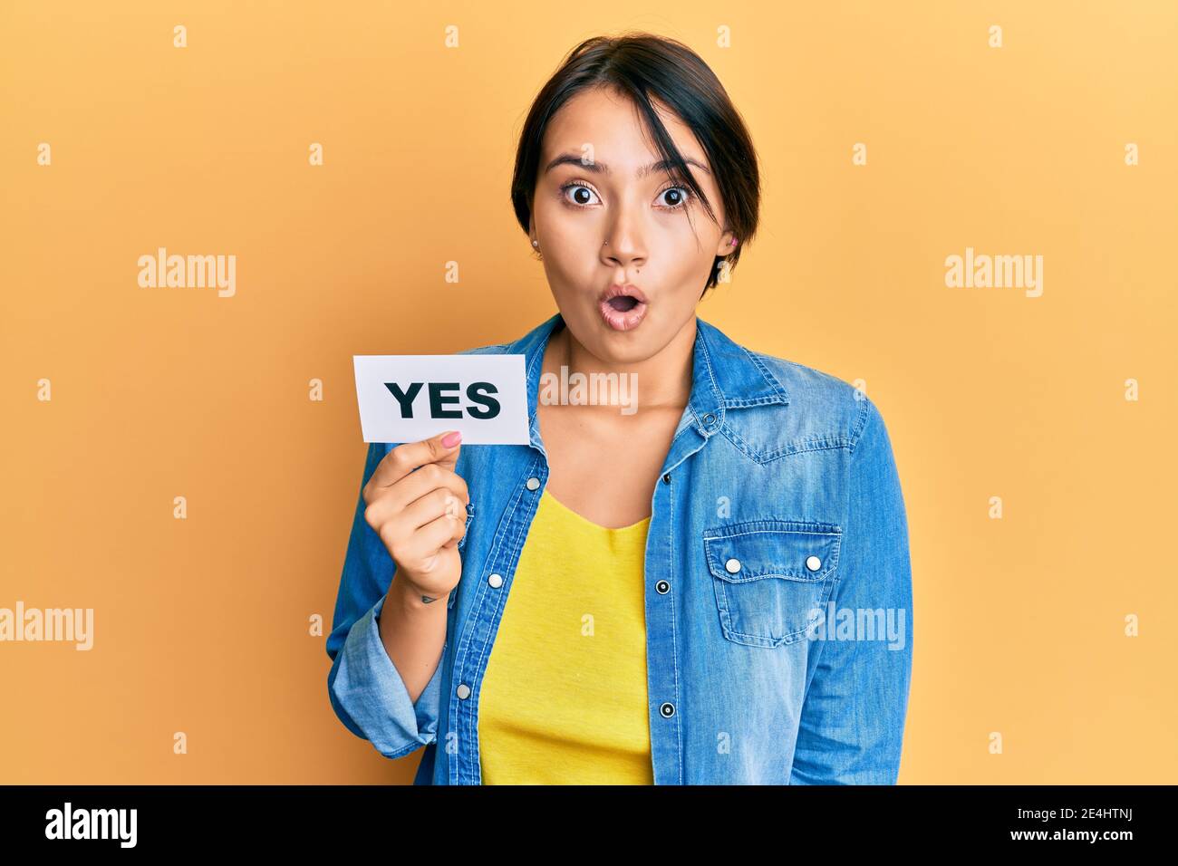 Beautiful young woman with short hair holding yes reminder scared and ...