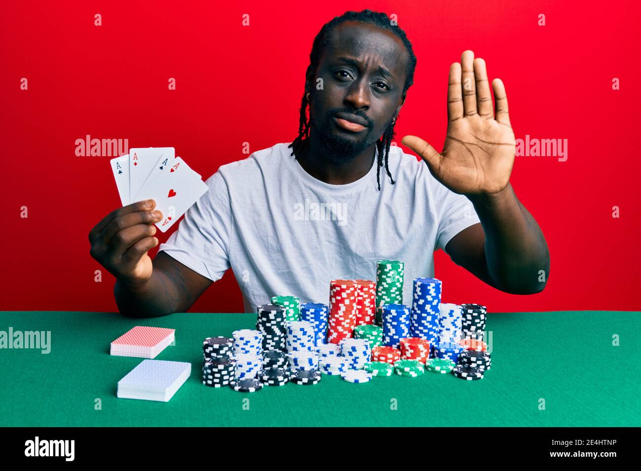 Handsome young black man playing poker holding cards with open hand ...