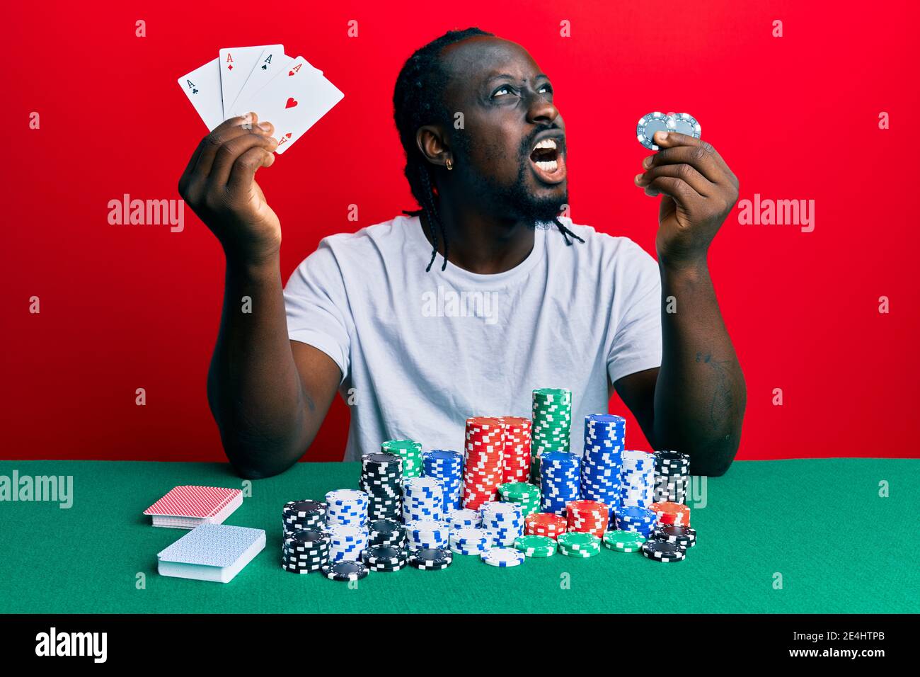 Handsome young black man sitting on the table with poker chips and ...