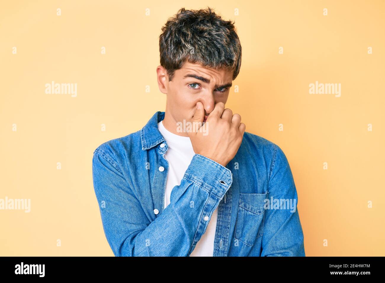 Young handsome man wearing casual clothes smelling something stinky and ...