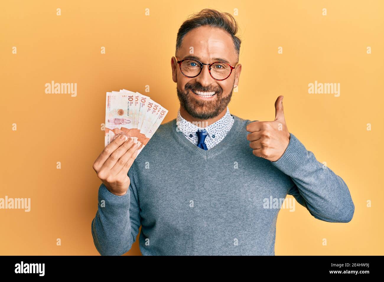 Handsome middle age man holding 10 colombian pesos banknotes smiling ...