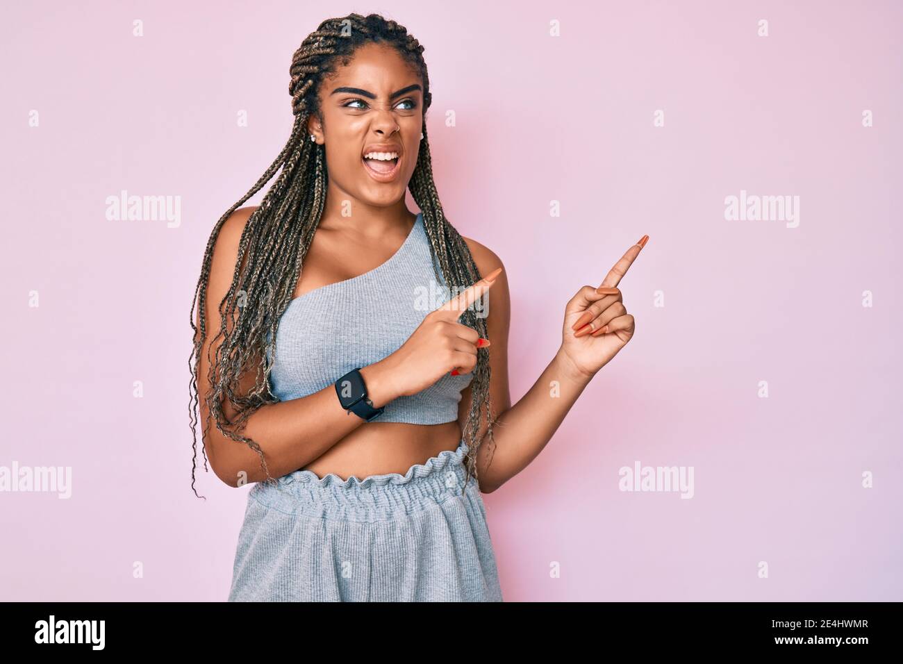 Young african american woman with braids wearing sports clothes angry ...