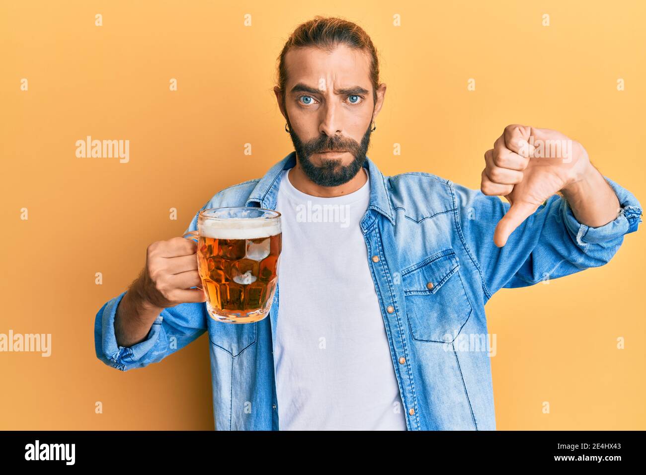 Attractive man with long hair and beard drinking a pint of beer with ...
