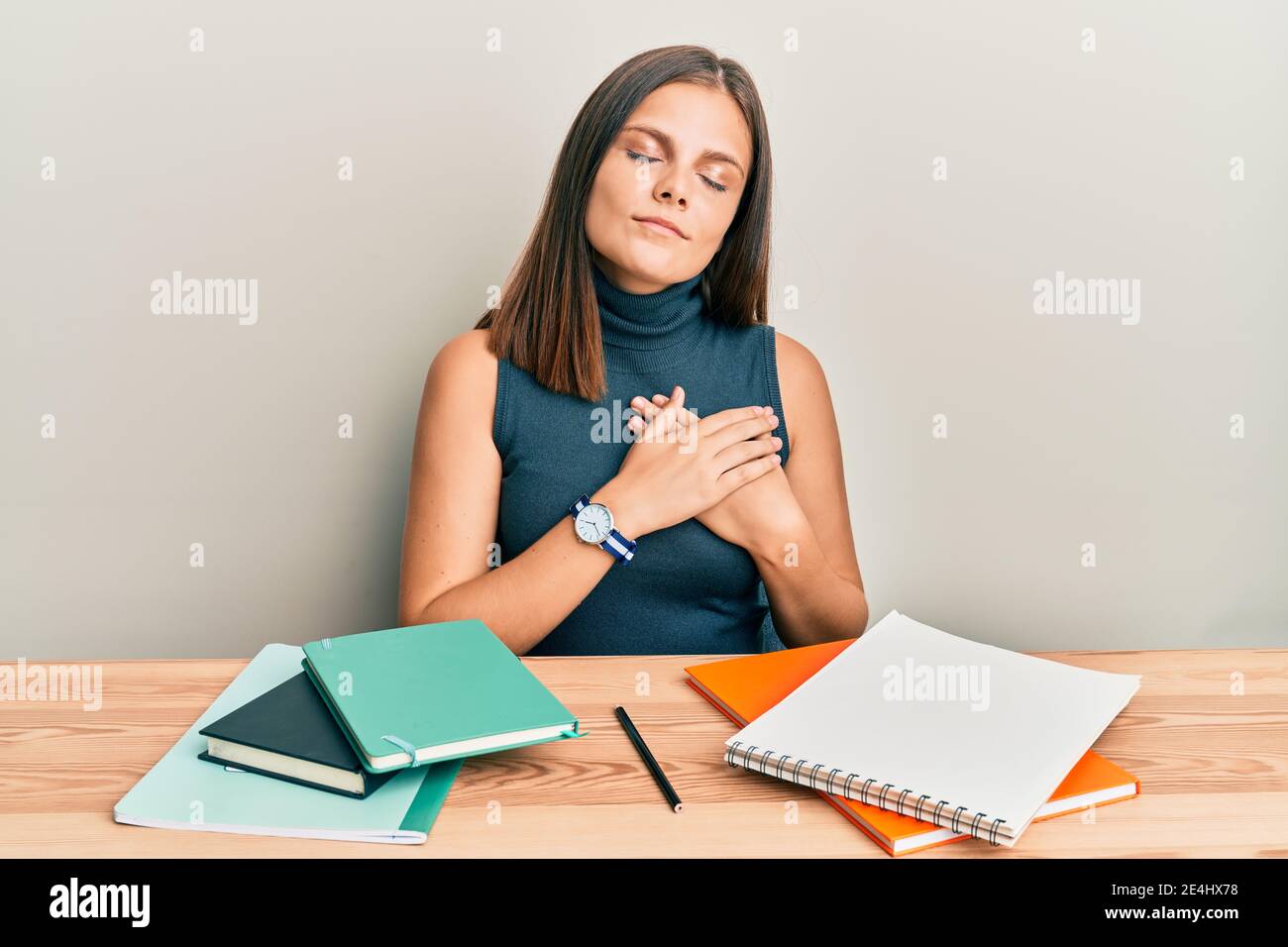 Young caucasian woman studying for exam smiling with hands on chest ...