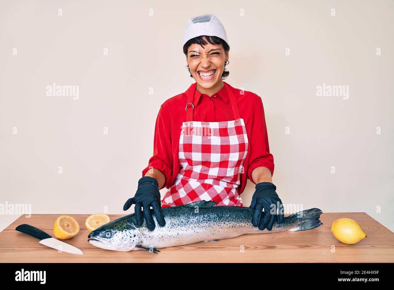 Beautiful brunettte woman fishmonger cooking fresh raw salmon smiling ...
