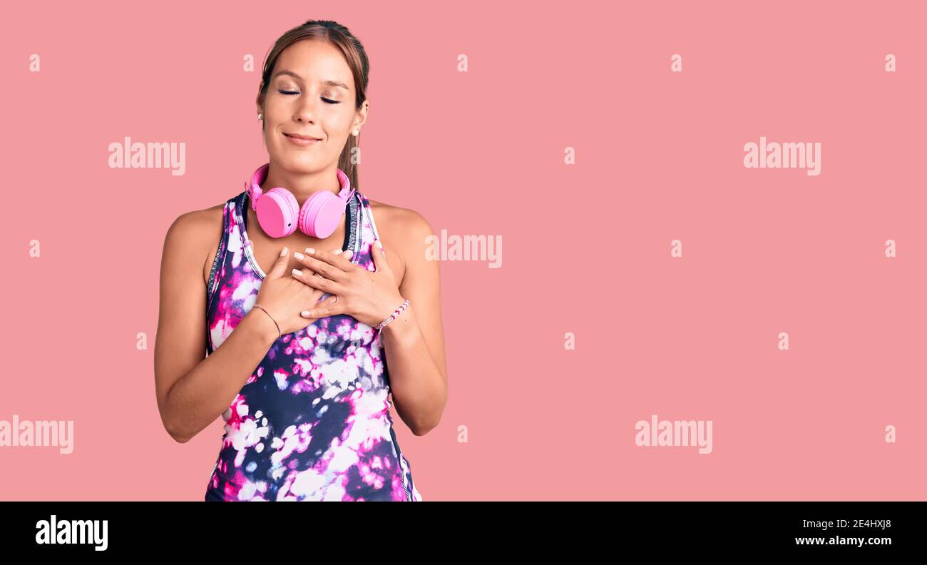 Young beautiful hispanic woman wearing gym clothes and using headphones ...