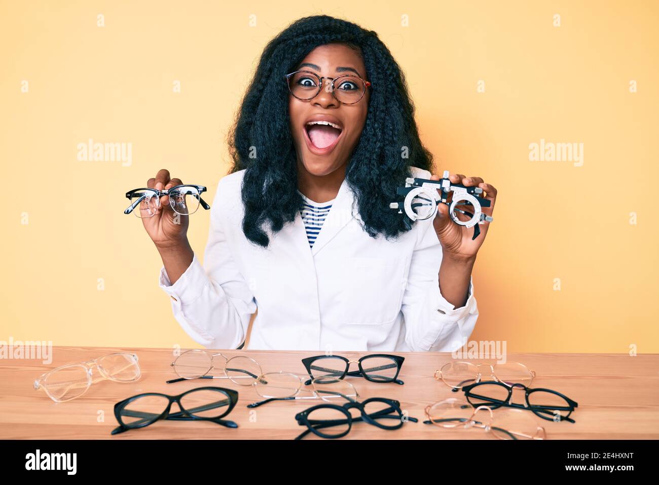 Young african american woman wearing optician uniform holding glasses ...