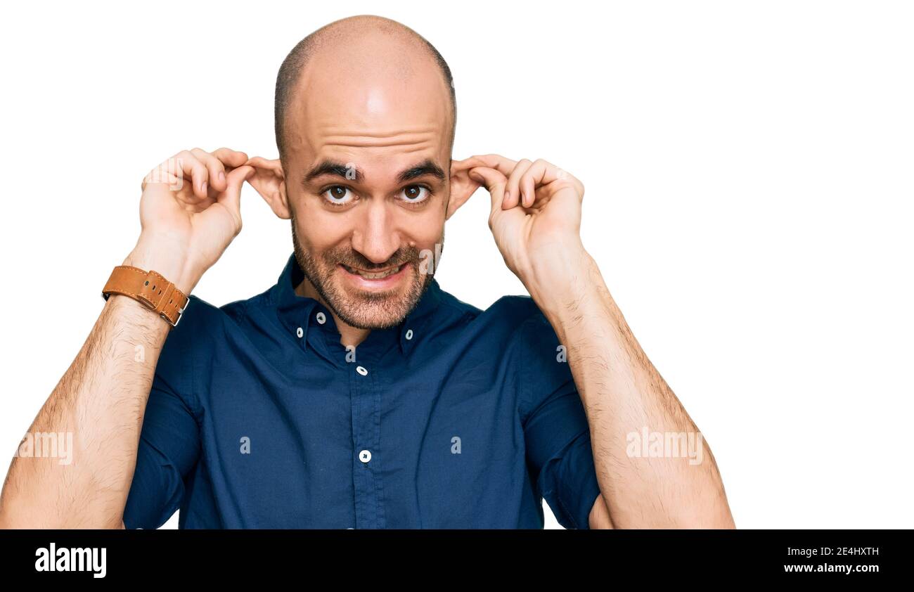 Young hispanic man wearing casual clothes smiling pulling ears with ...