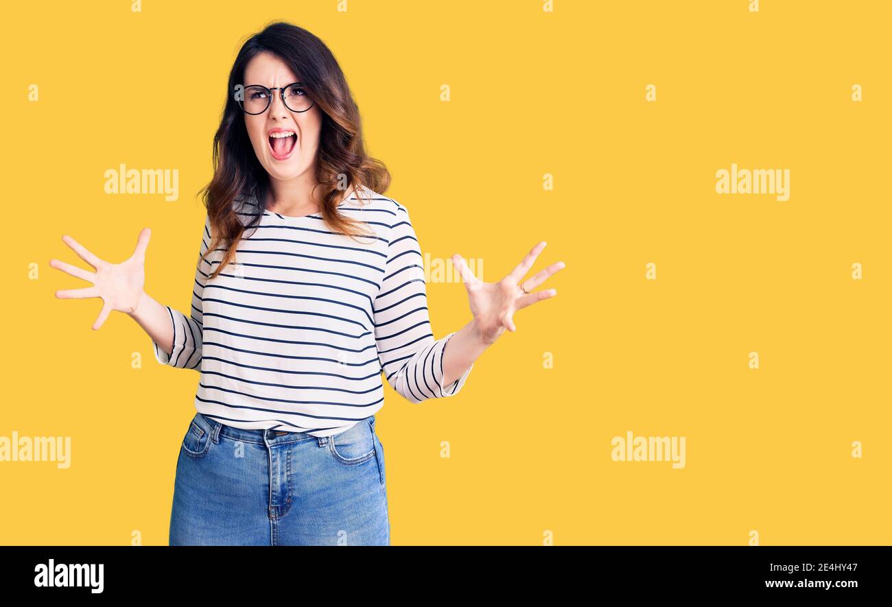 Beautiful young brunette woman wearing casual clothes and glasses crazy ...