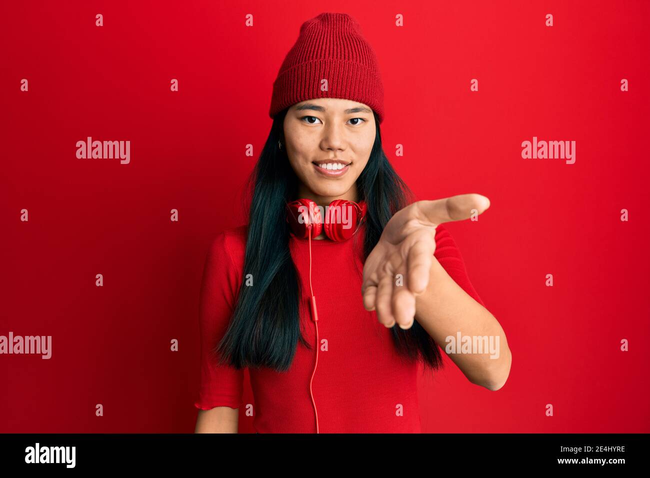 Young chinese woman listening to music using headphones smiling ...