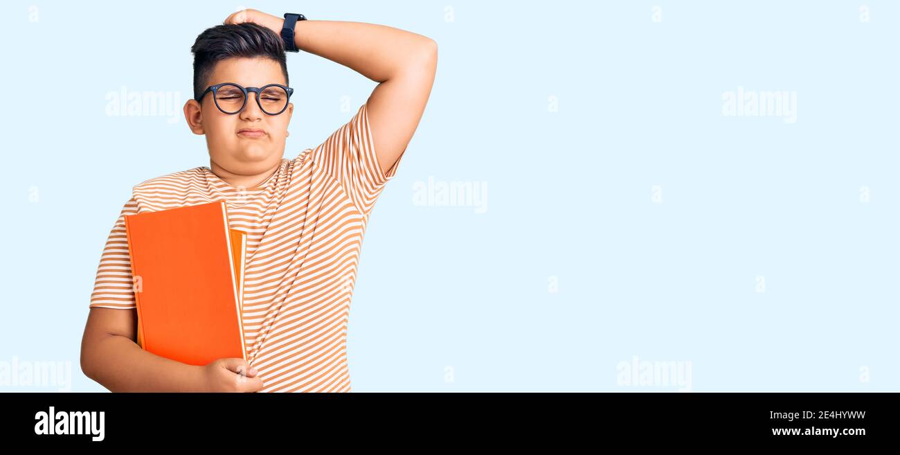 Little boy kid holding book wearing glasses confuse and wondering about ...