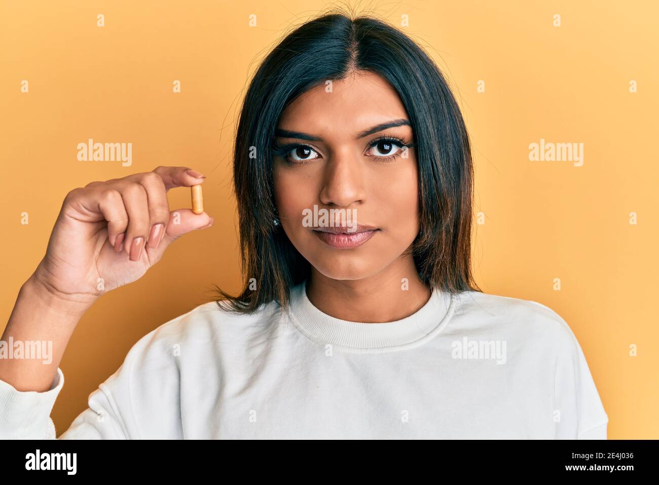 Young latin transsexual transgender woman holding pill thinking ...