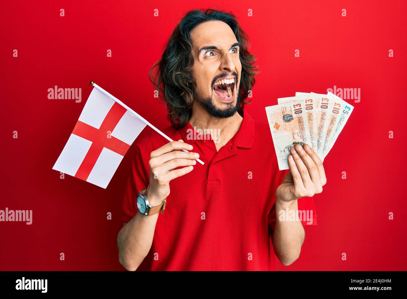 Young hispanic man holding england flag and pounds banknotes angry and ...