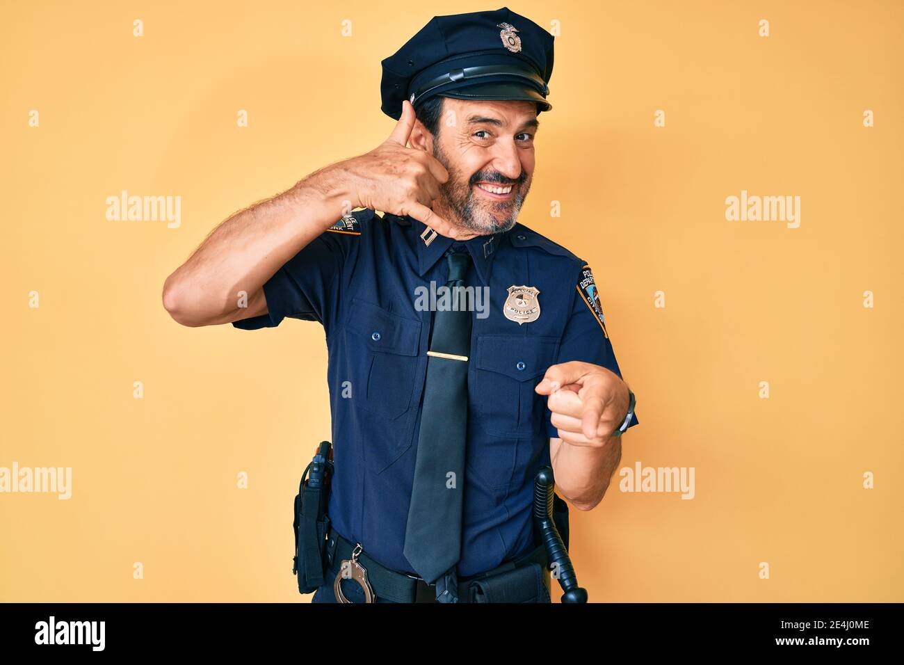 Mature male police officer communicating on walkie-talkie while holding ...