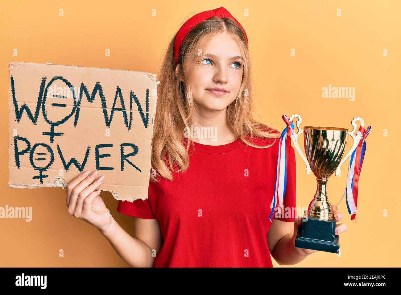 Beautiful young caucasian girl holding woman power banner and trophy ...