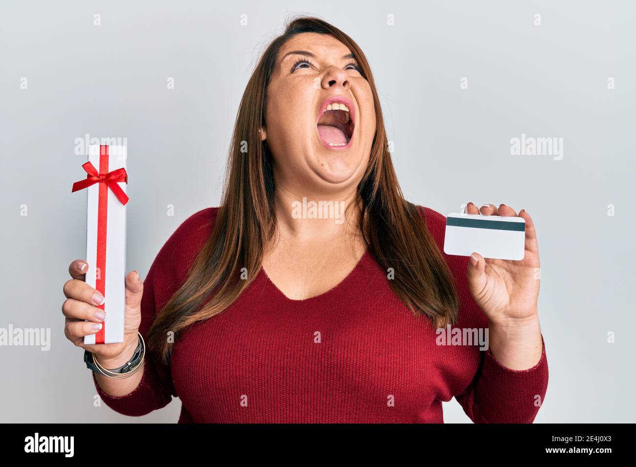 Beautiful brunette plus size woman holding gift and credit card angry ...