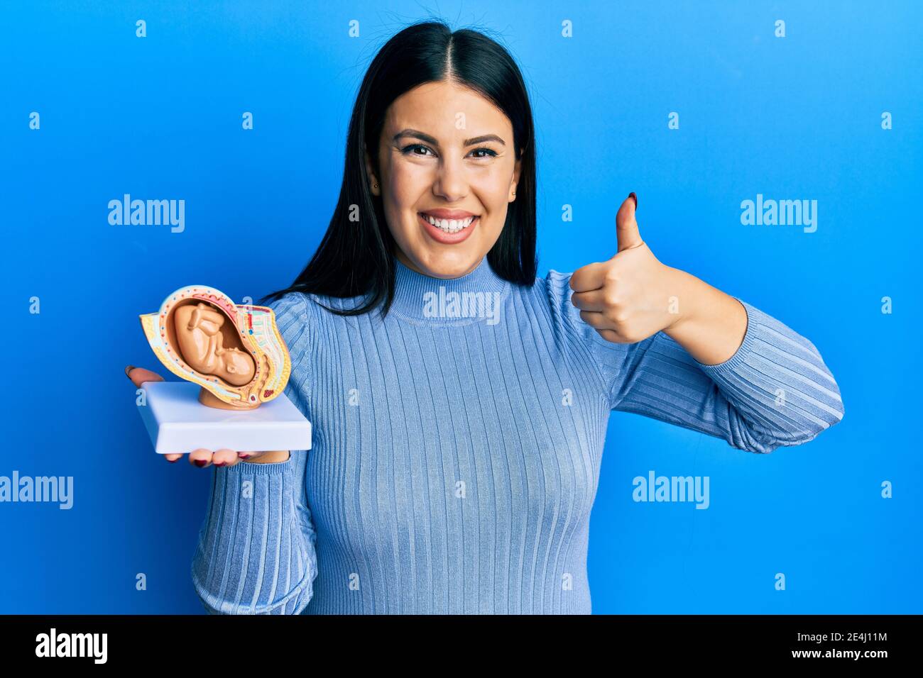 Beautiful brunette woman holding anatomical model of female uterus with ...