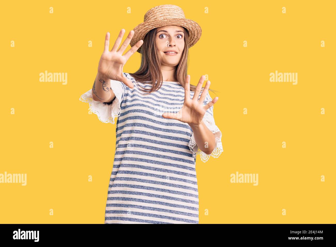 Beautiful caucasian woman wearing summer hat afraid and terrified with ...