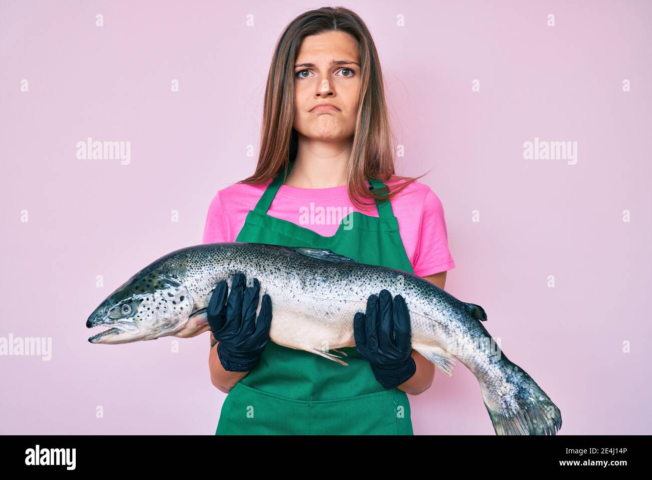 Beautiful caucasian woman fishmonger selling fresh raw salmon depressed ...
