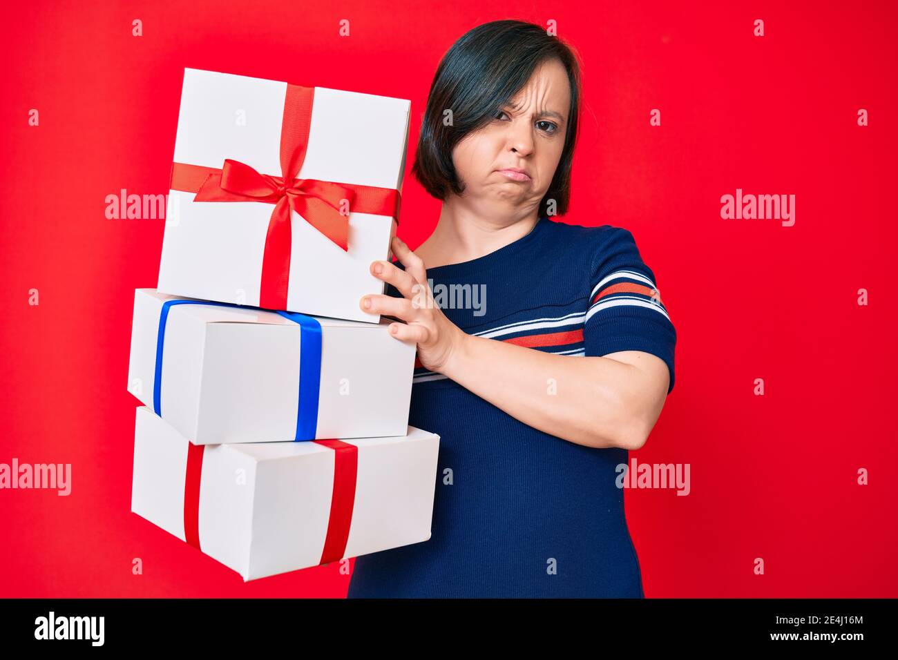 Brunette woman with down syndrome holding gifts skeptic and nervous ...