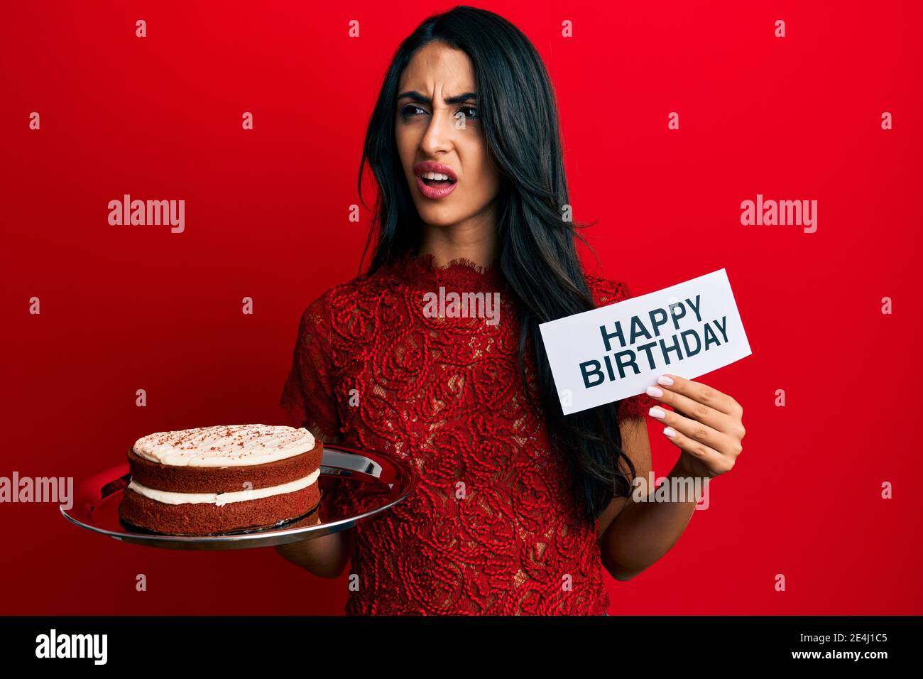 Beautiful hispanic woman celebrating birthday with cake angry and mad ...