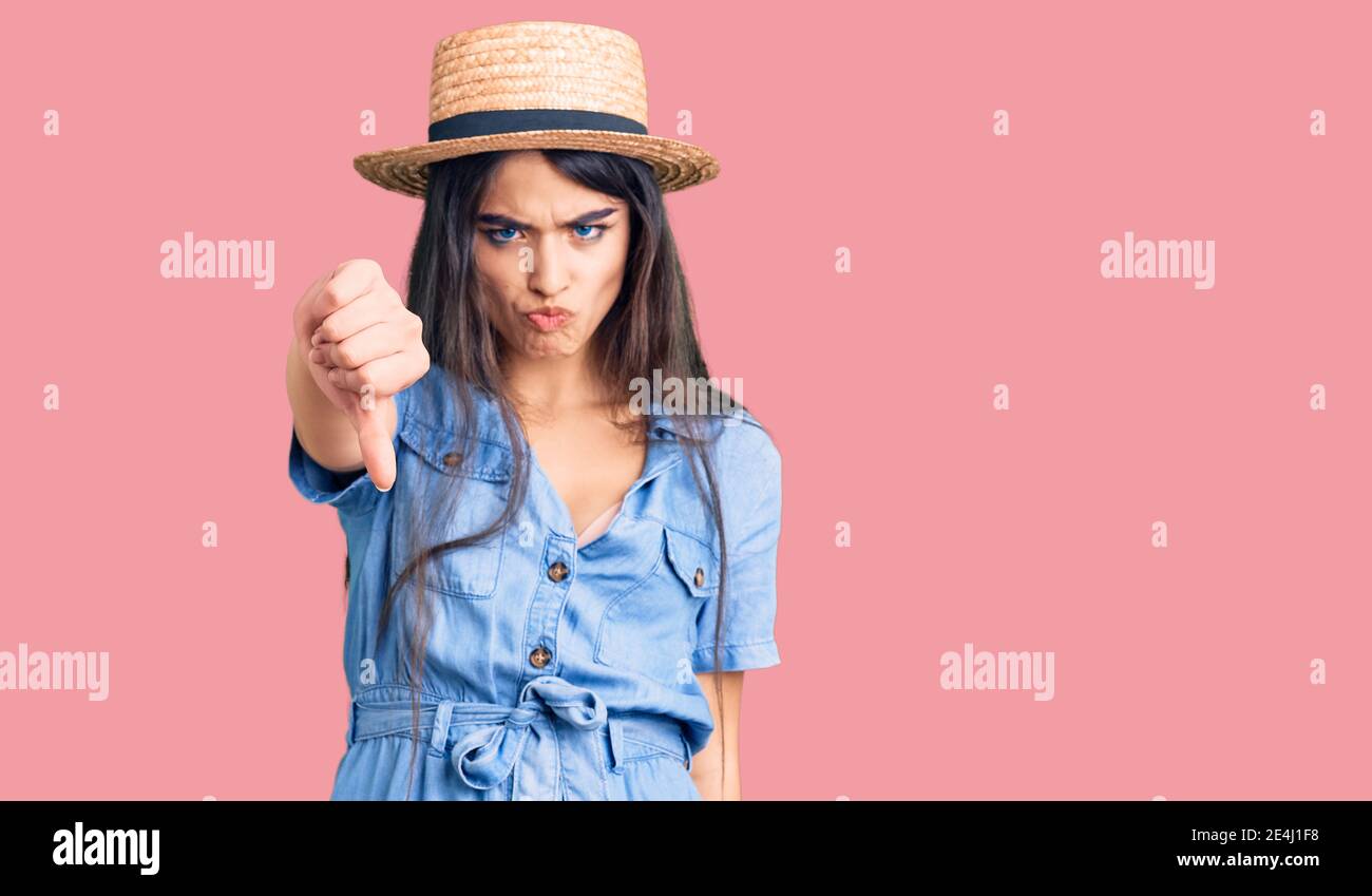 Brunette teenager girl wearing summer hat looking unhappy and angry ...