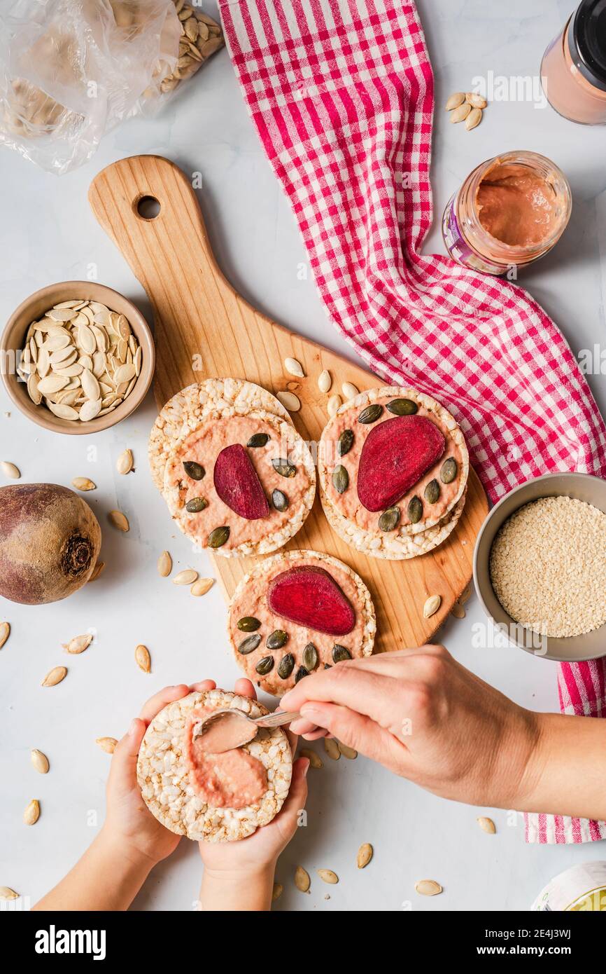 Crispy puffed rice cakes on table hummus spread and tomato and beet ...