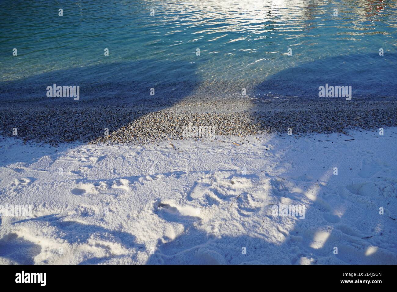 Snow white sand and pebbles on the ocean coast near the emerald ocean ...