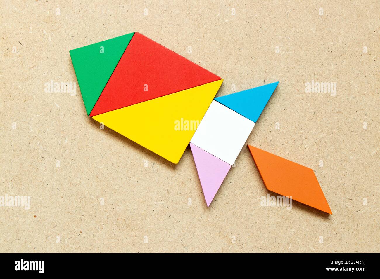 Color tangram puzzle in missile or rocket shape on wood background ...