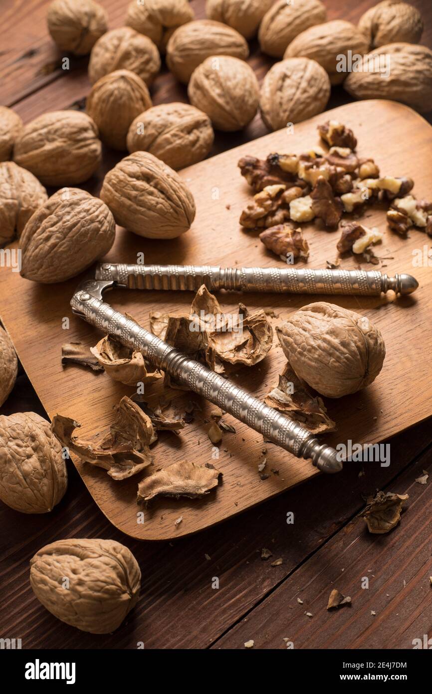 A close up photo of whole walnuts in their shell, broken shells, and ...