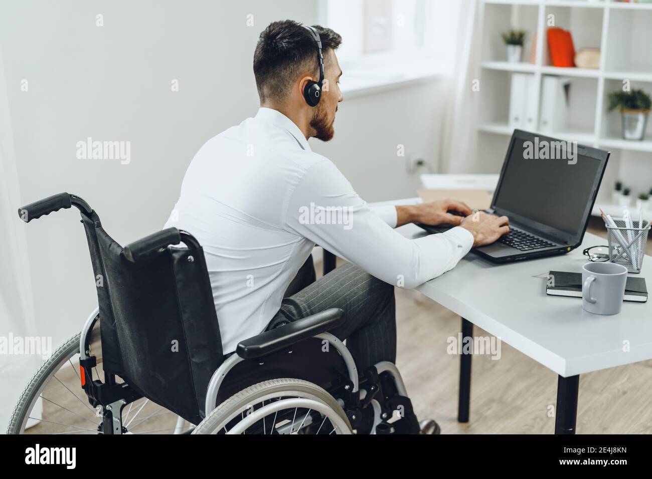 Disabled man in a wheelchair using laptop Stock Photo - Alamy