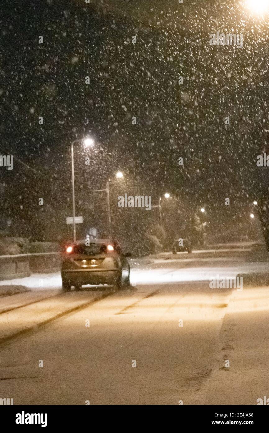 Falling snow on street at night. Driving car in snow with tyre tracks ...